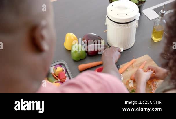 Preparing fresh vegetables in kitchen, couple composting vegetable ...