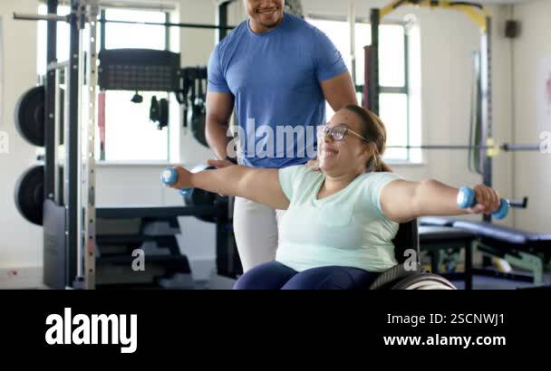Assisting woman with paraplegia in wheelchair, personal trainer guiding rehabilitation exercises ...