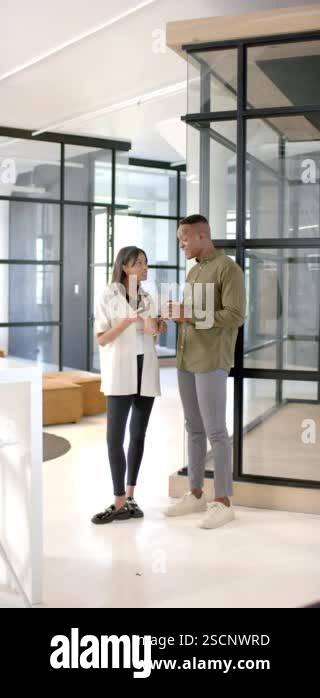 Vertical video: Discussing work, colleagues looking at smartphone in ...