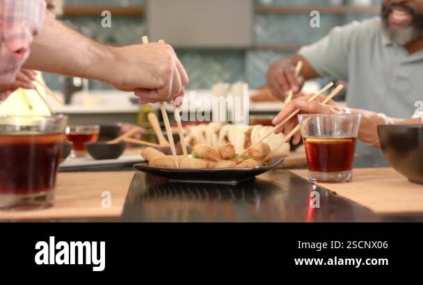 Eating spring rolls with chopsticks, friends enjoying Asian cuisine ...