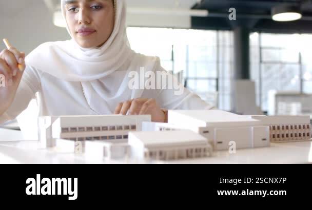 Architect working on building model in office, focusing on design ...
