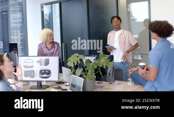 Team collaborating in office, discussing VR headset designs on computer ...
