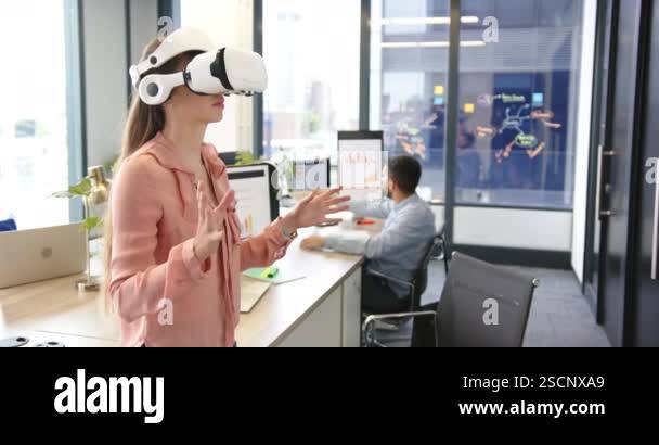Using VR headset, woman interacting with virtual environment in modern office. Technology ...