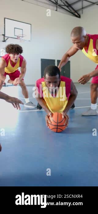 Vertical video: Playing basketball, male athlete diving for ball while ...