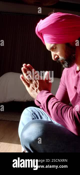 Vertical video: Praying with hands together, man in turban in ...