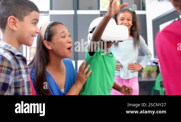 In school, children using VR headset with teacher guiding them in ...