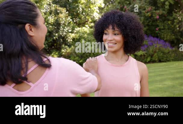 Smiling woman in park, friend placing hand on her shoulder, enjoying ...