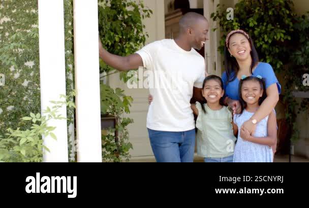 Smiling family of four standing together outside their home, enjoying time. togetherness ...
