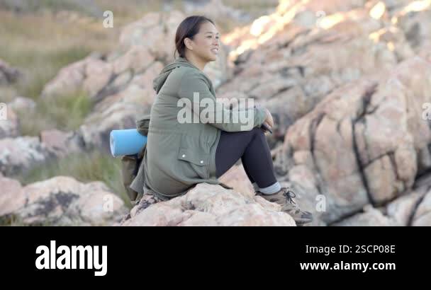 Sitting on rocky terrain, woman enjoying nature during mountain hike ...