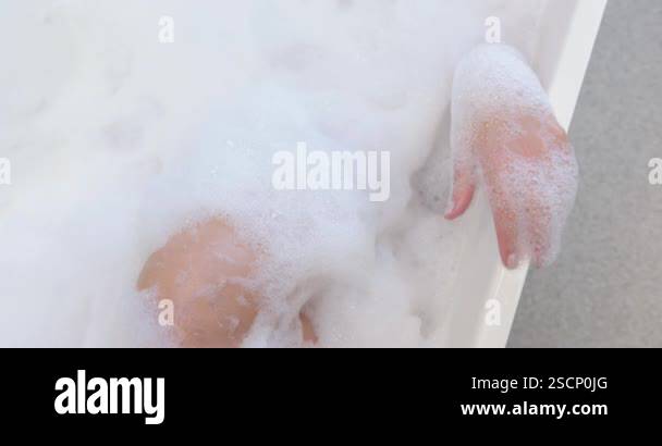 Relaxing in bathtub, woman enjoying bubble bath with hands visible ...