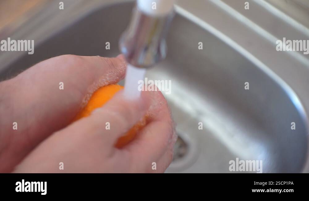 Hands are washed under a tap from a tap over the kitchen sink a ripe ...