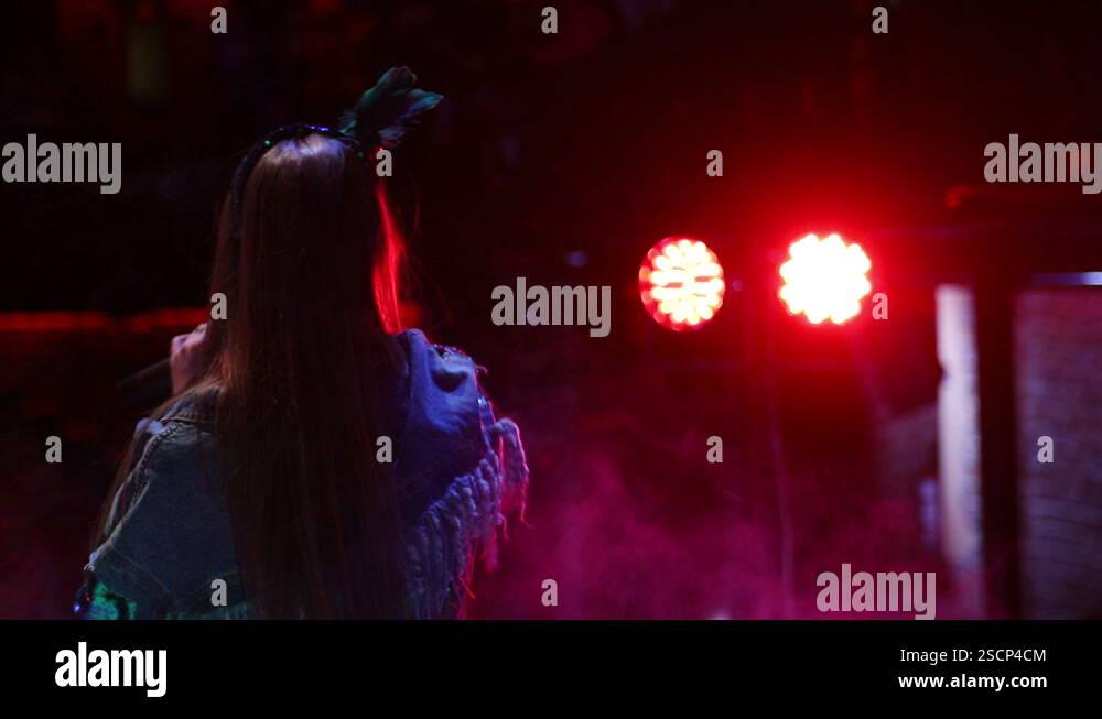 Girl who sings and dances on stage, Back view of singer. Light and ...
