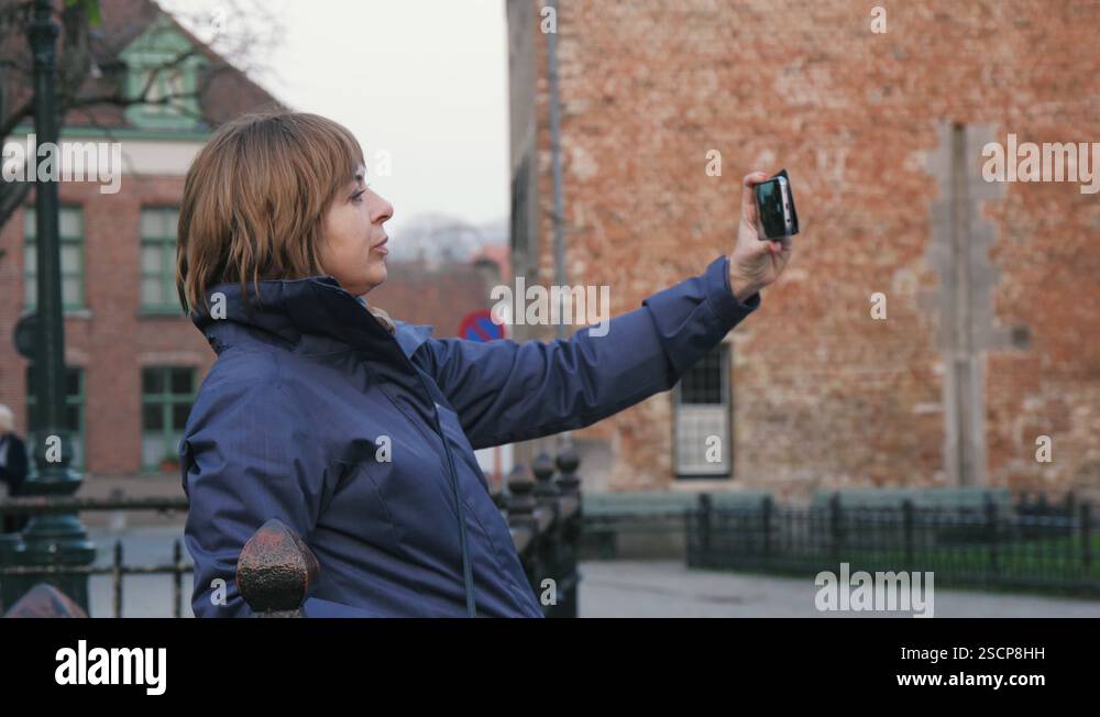 Smiling woman taking a selfie at a water canal in Brugge in spring in ...