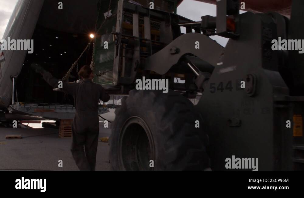 Loadmaster directing forklift truck operator loading cargo onto C-130 ...