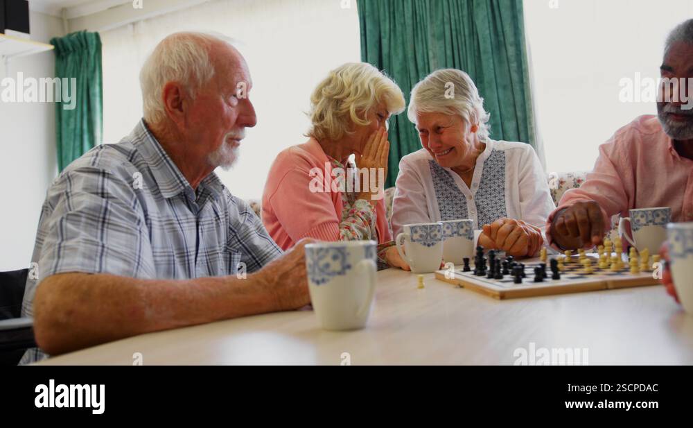 Active mixed-race senior people playing chess game in the nursing home ...