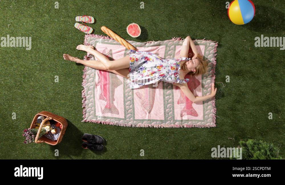 MS, Lockdown, woman stretching and eating an apple on a blanket at park ...