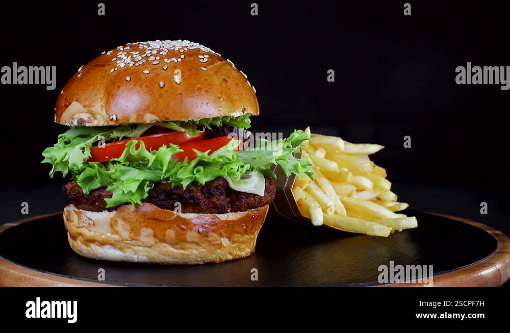 Fast food food. Berger with French fries, spin on wooden Board on black ...