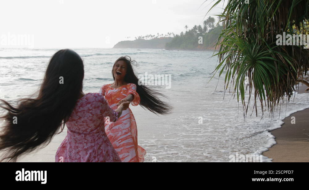 Two Young South Asian sisters with lush and beautiful hair whirl around ...