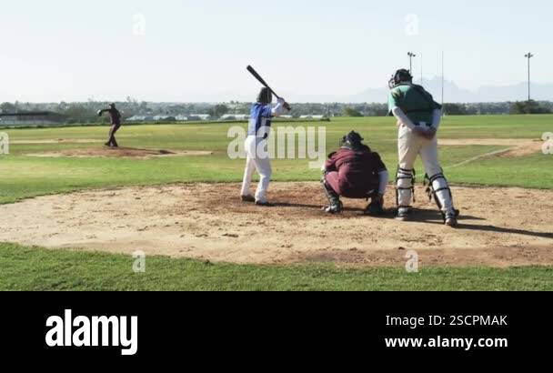 Multiracial male players and umpire playing baseball on a pitch, slow ...