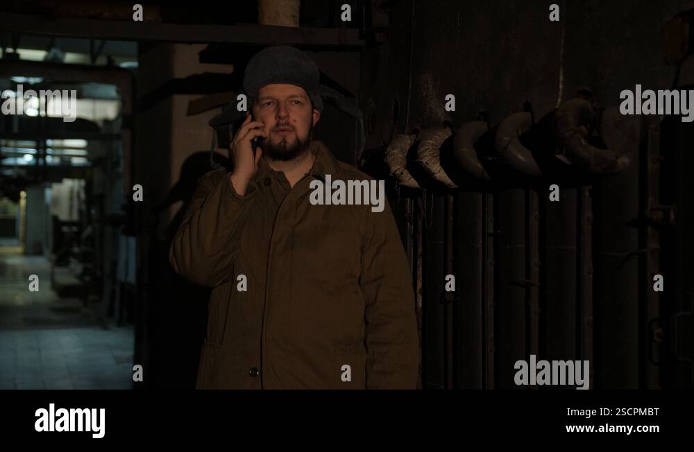 Russian man in a hat with earflaps, talking on the phone in a dark ...