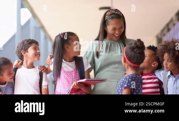Teacher smiling with group of diverse students holding books at school ...
