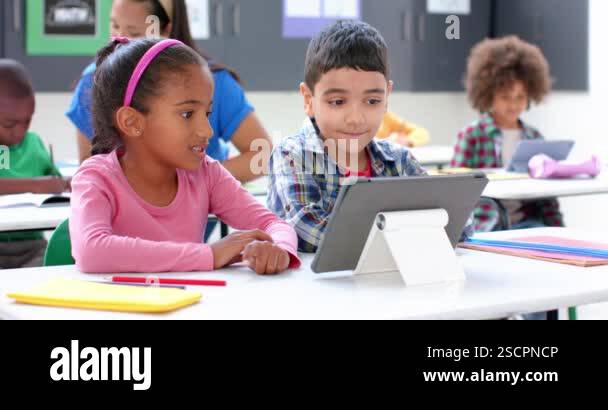 In school, children using tablet and studying together in classroom ...