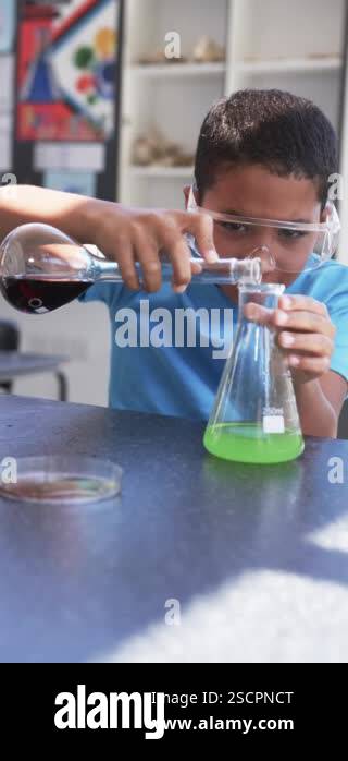 Vertical video: In school, child pouring liquid into beaker during ...
