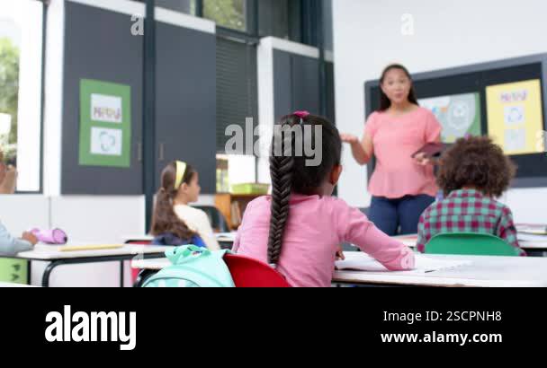 In school, student raising hand to ask question while teacher smiles ...