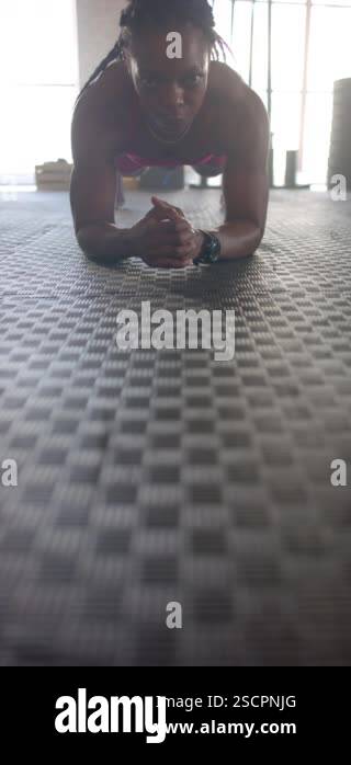 Vertical video: Planking on gym floor, woman focusing on core strength ...