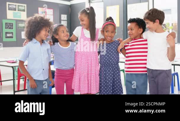 In school, group of children standing together and smiling in classroom ...