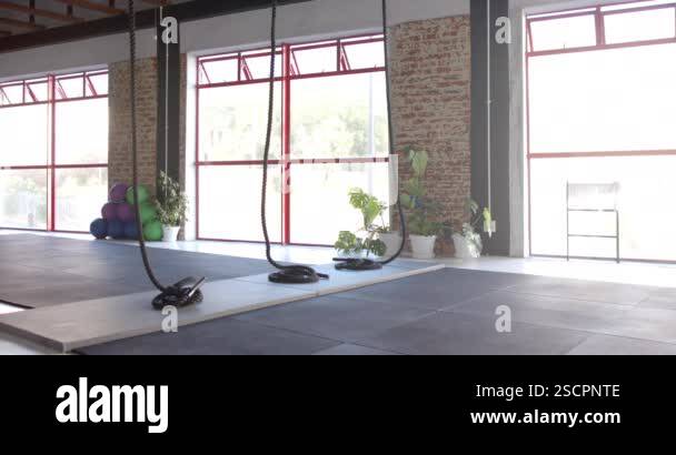 Large windows let sunlight into spacious gym with ropes and mats ...