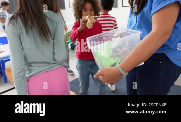 In school, children participating in recycling activity with teacher in ...