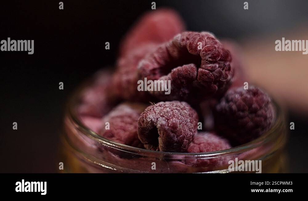 Raspberries are getting placed on surface of pink mass in glass jar as ...