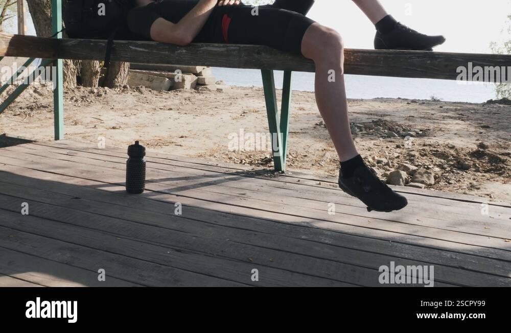 Strong athletic professional cyclist lying on bench with water bidon ...