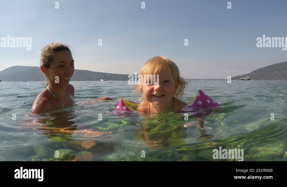 Happy mother and her child swimming in sea. Happy family of mum and ...