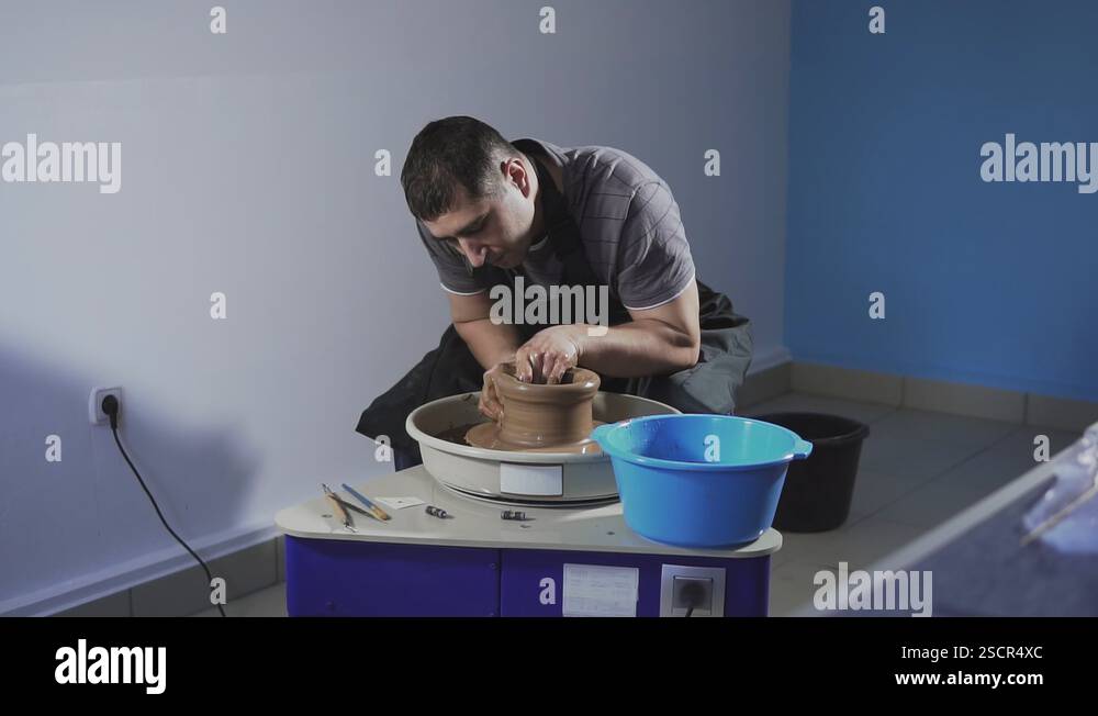 Potter creates product on potter's wheel. Man gently create jug from ...