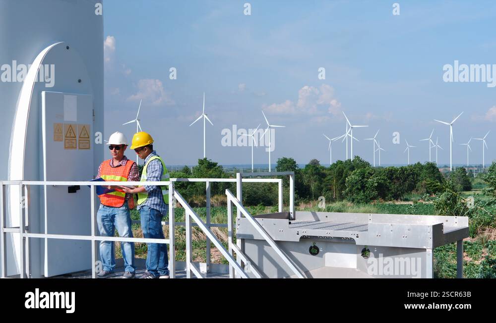 Two Asian engineers are checking the operation of wind turbines in wind ...