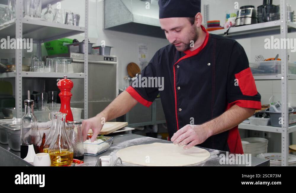 Restaurant kitchen. A chef preparing a dough for the pizza. Adding ...