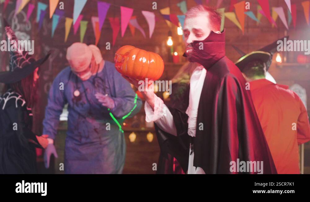 Man in a ghoul or vampire costume is dancing with a jack-o-lantern in ...