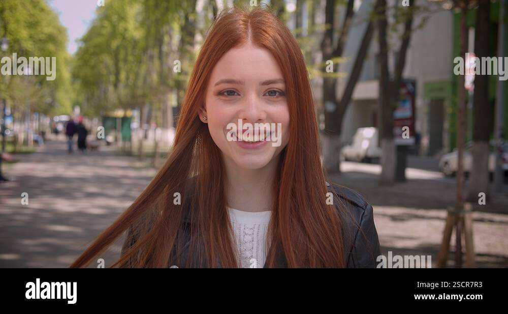 Beautiful ginger girl in leather jacket turns to camera and smiles ...
