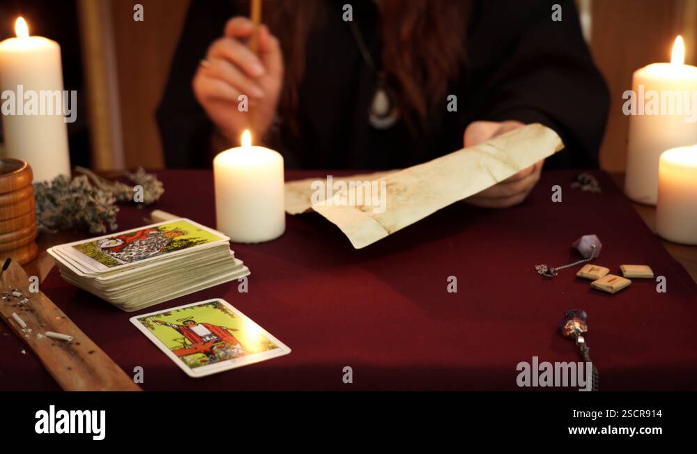 A witch ignite candle, read spell and drip wax on the paper. Occult ...