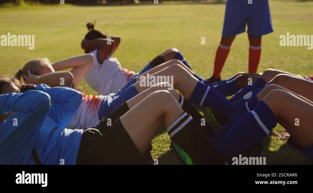 Female soccer players doing sit up exercises while captain gives ...