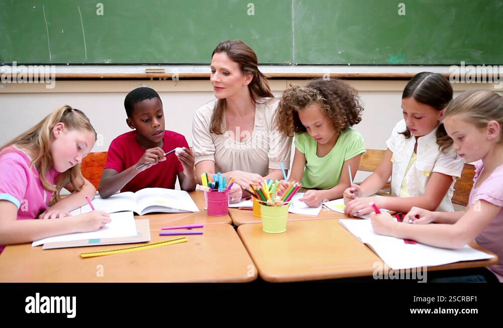 Teacher sitting at a table with pupils Stock Video Footage - Alamy