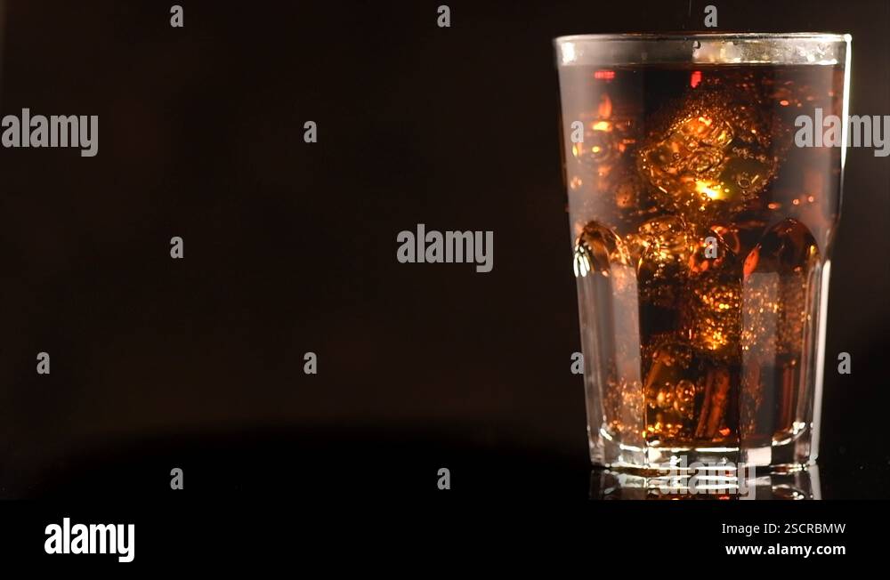 Coke with ice cubes closeup. Glass of fizzy cola rotated over black ...