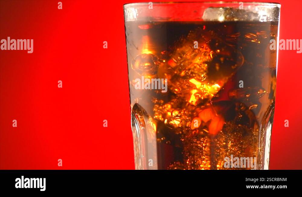 Coke with ice cubes closeup. Glass of fizzy cola rotated over red ...