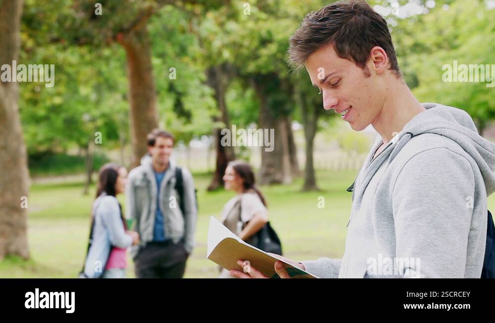 Man reading a book before looking at the camera while smiling as he ...