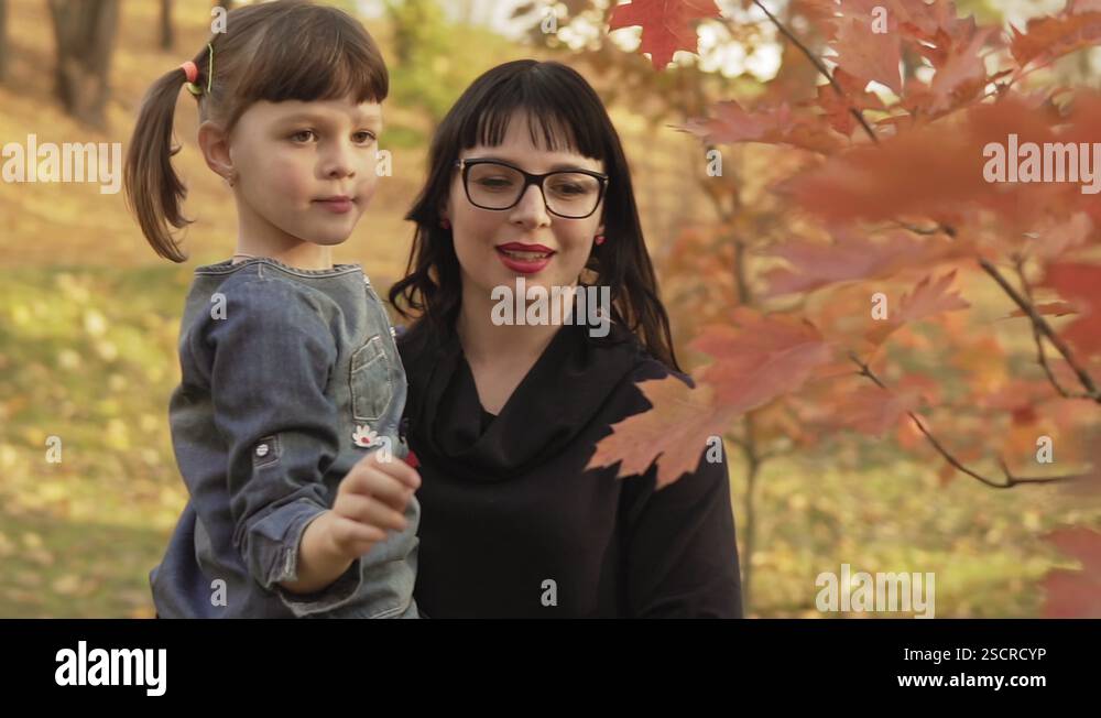 Mother and her happy little daughter in autumn park. Mother holding ...