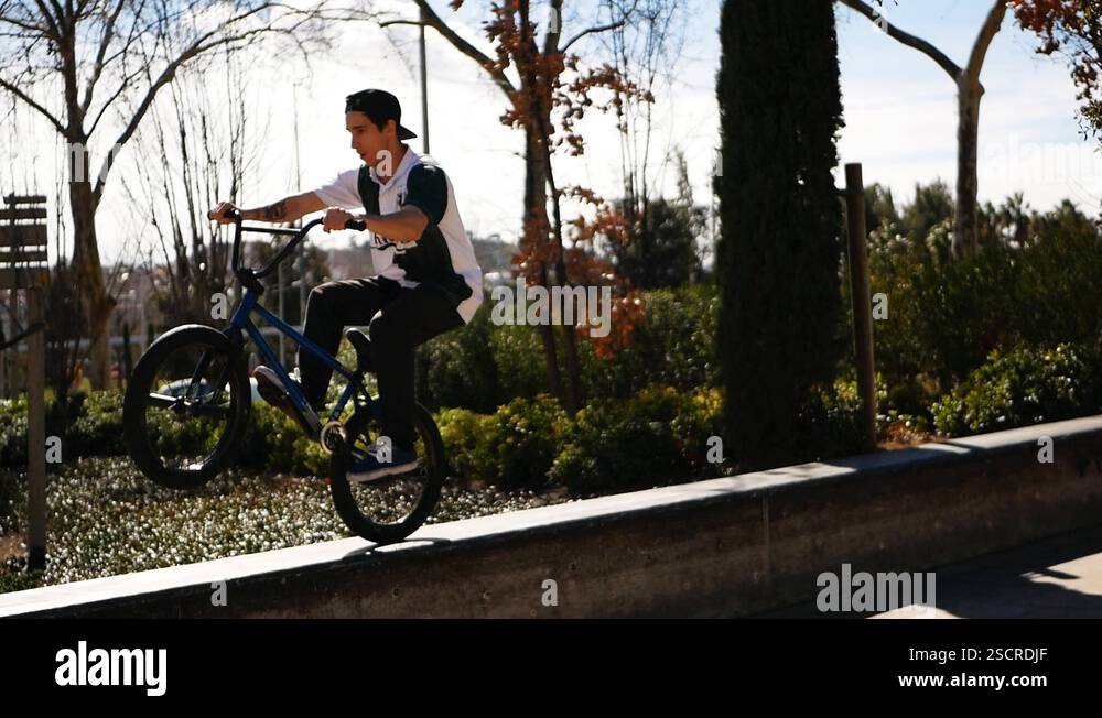 Extremal guy cyclist is riding in street on pathway and jumping on wall ...