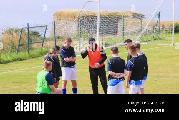 Male and female soccer players listening to male coach giving ...