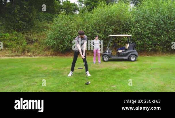 Two male and female golf players playing golf together, hitting the ...